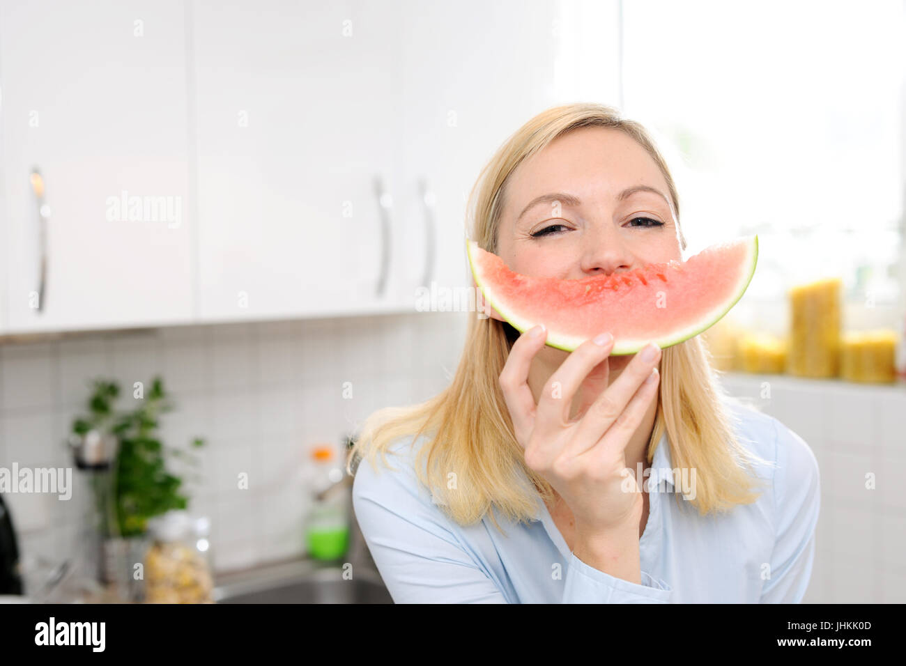 blonde cheerful woman eating watermelon Stock Photo - Alamy