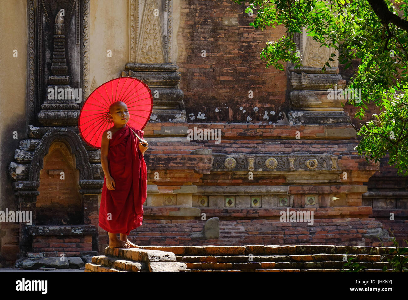 A Buddhist novice monk with the umbrella standing at ancient temple in ...