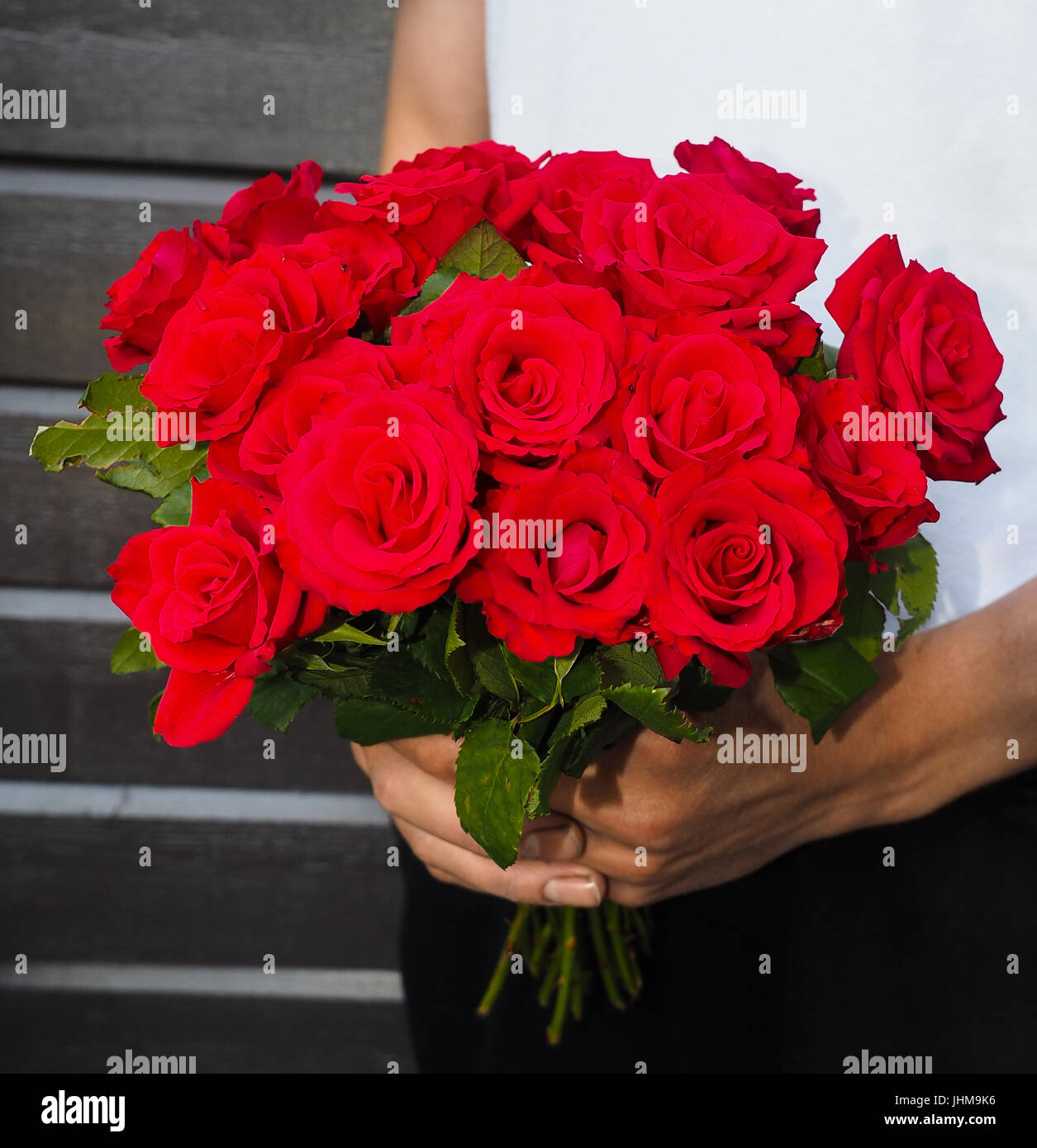Male person holding a beautiful bouquet of red roses wearing white ...