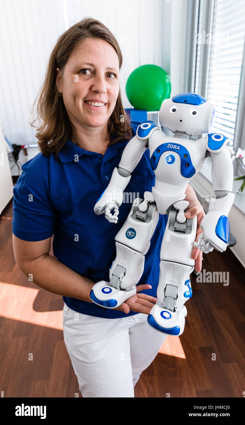 Physiotherapist Stefanie Finn holding the robot Zora in a therapy room ...