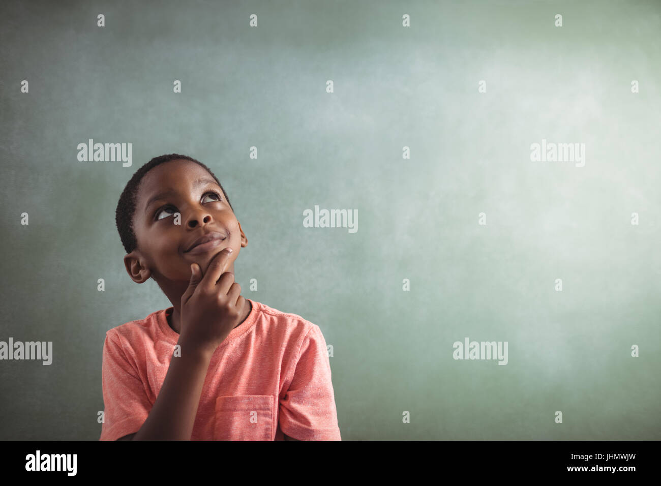 Thoughtful boy standing against greenboard in classroom Stock Photo - Alamy
