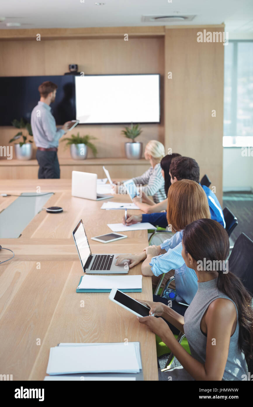 Business people using laptop and digital tablets at conference table ...