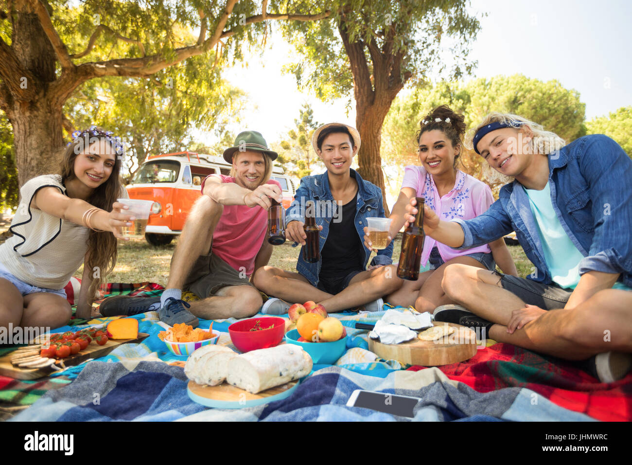 Portrait of smiling friends showing beer bottles and glasses while ...
