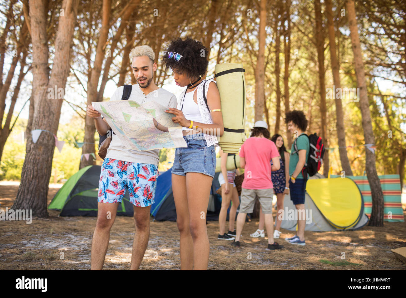 Couple reading map field with standing in background at campsite Stock ...