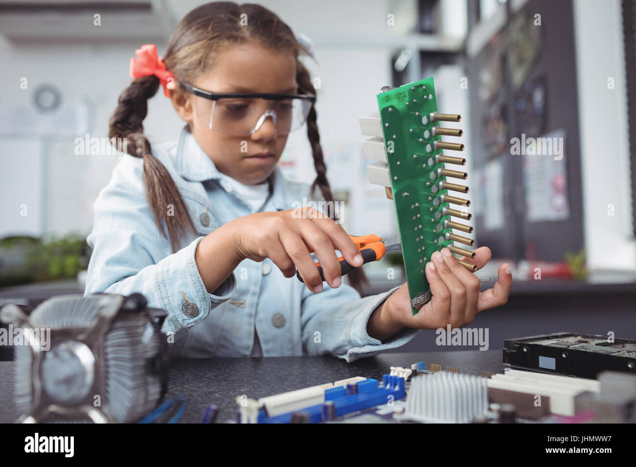 Concentrated elementary girl assembling circuit board on desk at ...