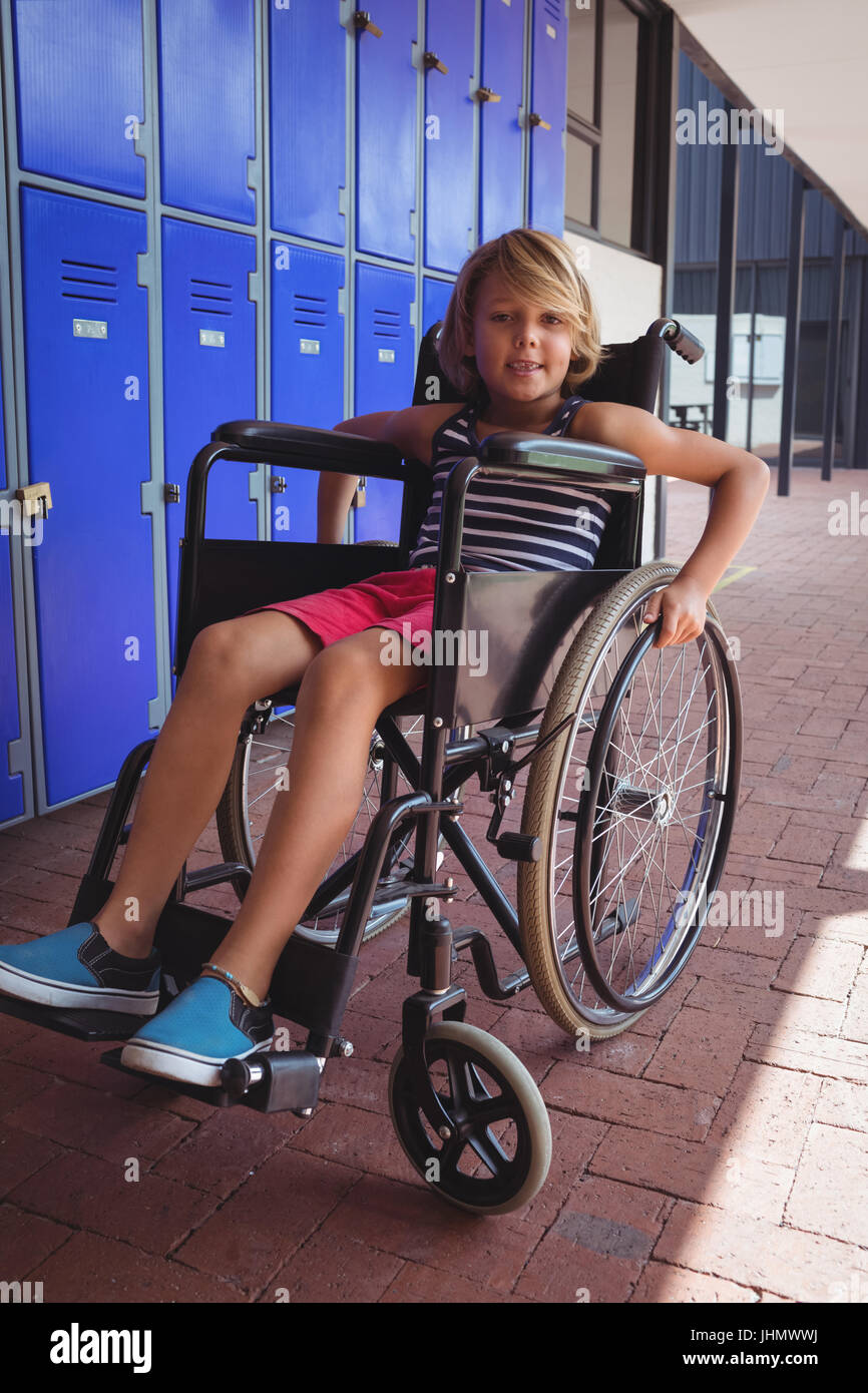 Portrait of student sitting on wheelchair in corridor at school Stock ...