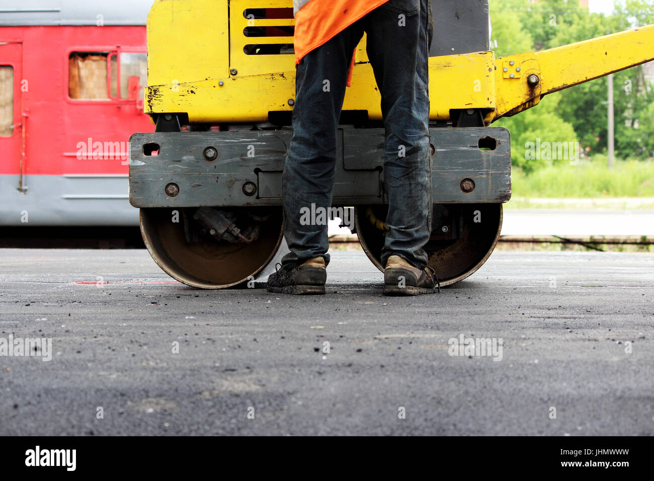 A small compactor covers with asphalt to platform at the railway ...