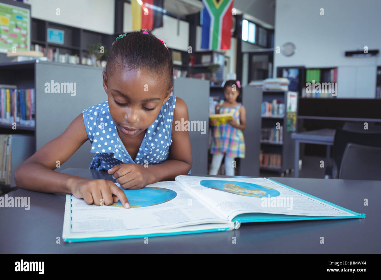 Girl reading book at desk in library Stock Photo - Alamy