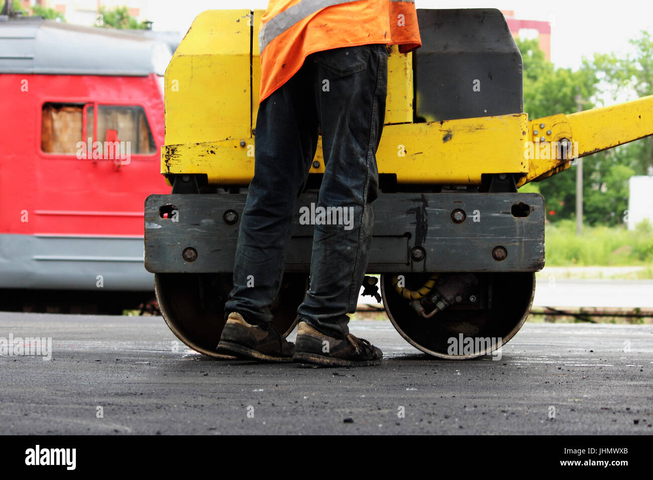 A small compactor covers with asphalt to platform at the railway ...