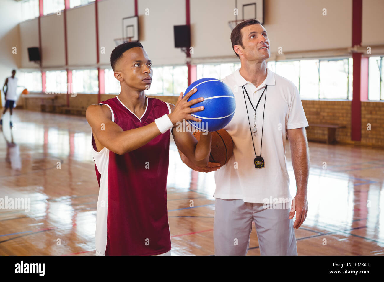 Coach training teenage boy while standing in basketball court Stock ...