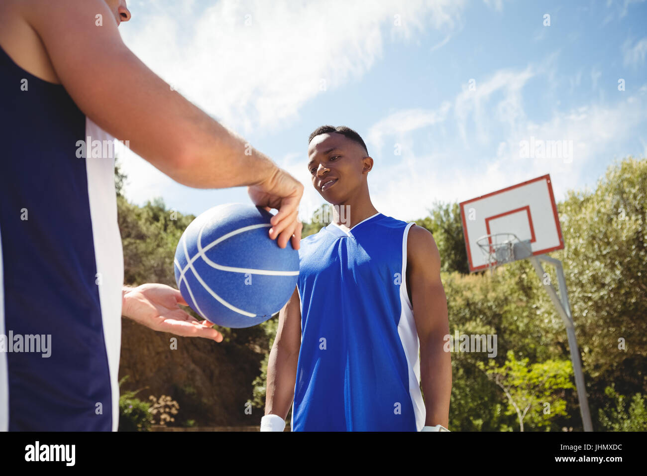 Man showing basketball to friend while playing in court Stock Photo - Alamy