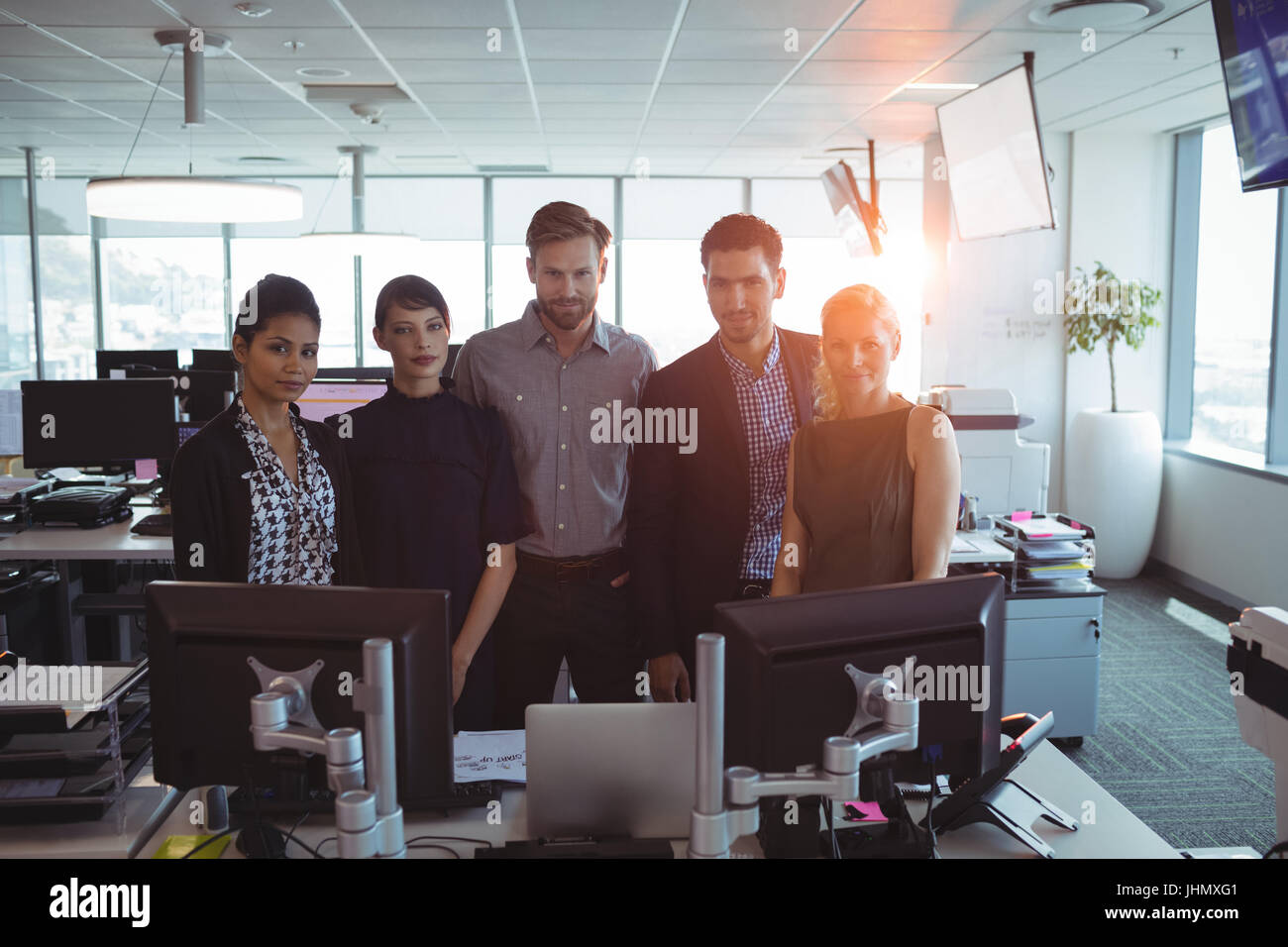 Portrait of business colleagues standing together by desk at office ...