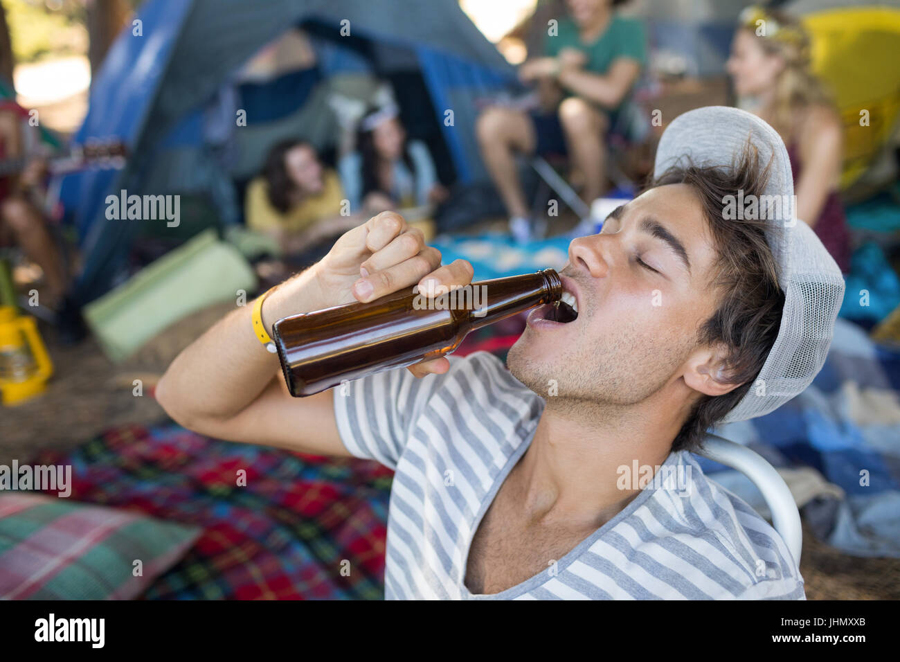 Young man drinking beer from bottle at campsite Stock Photo - Alamy