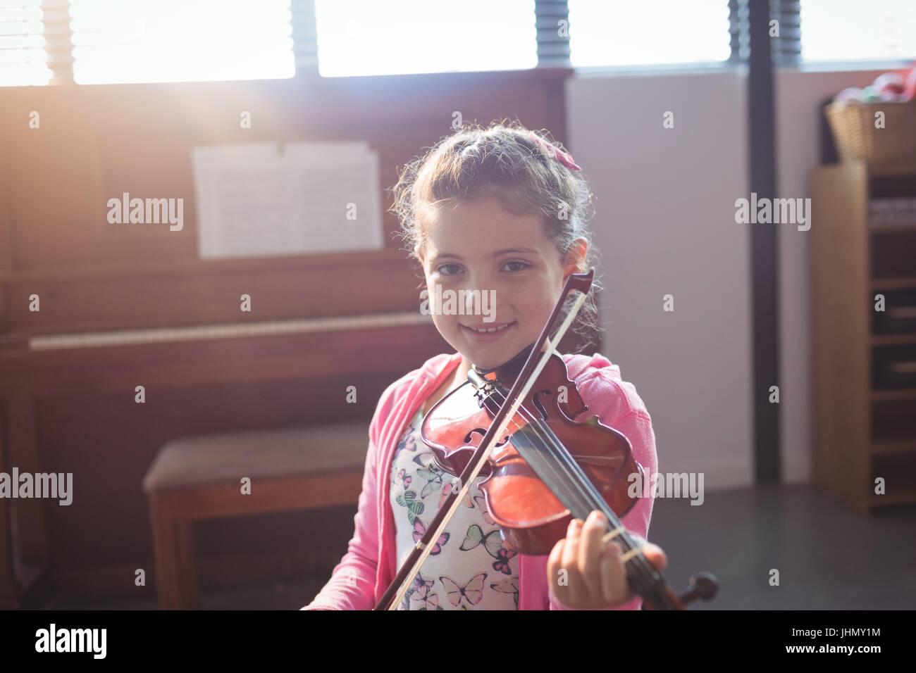 Portrait of smiling girl student rehearsing violin in music class Stock ...