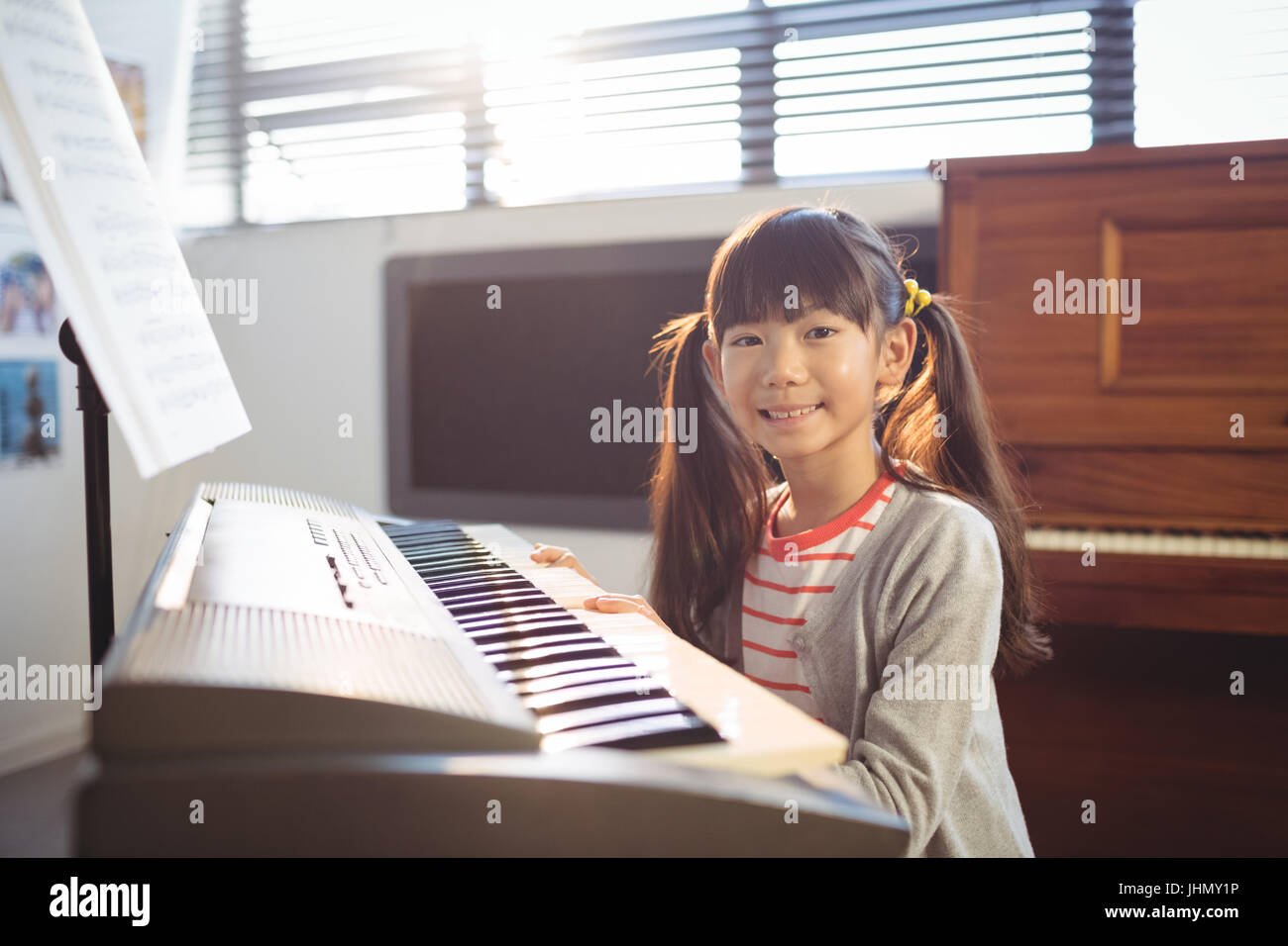 Portrait of smiling girl practicing piano in class at school Stock ...