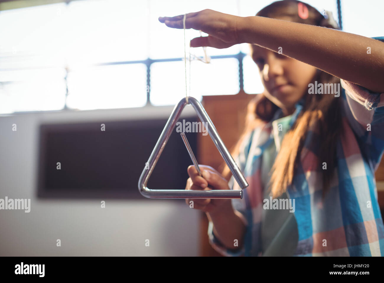 Girl playing triangle in classroom at music school Stock Photo - Alamy
