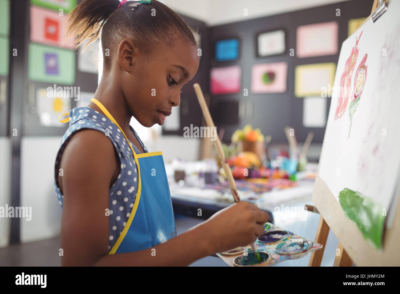 Side view of focused girl painting on canvas in classroom Stock Photo ...