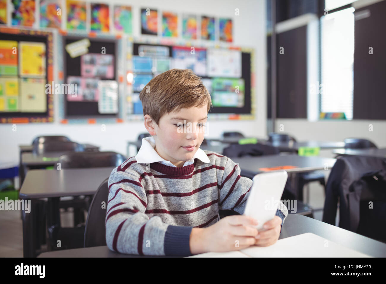 Boy using digital tablet at desk in classroom Stock Photo - Alamy