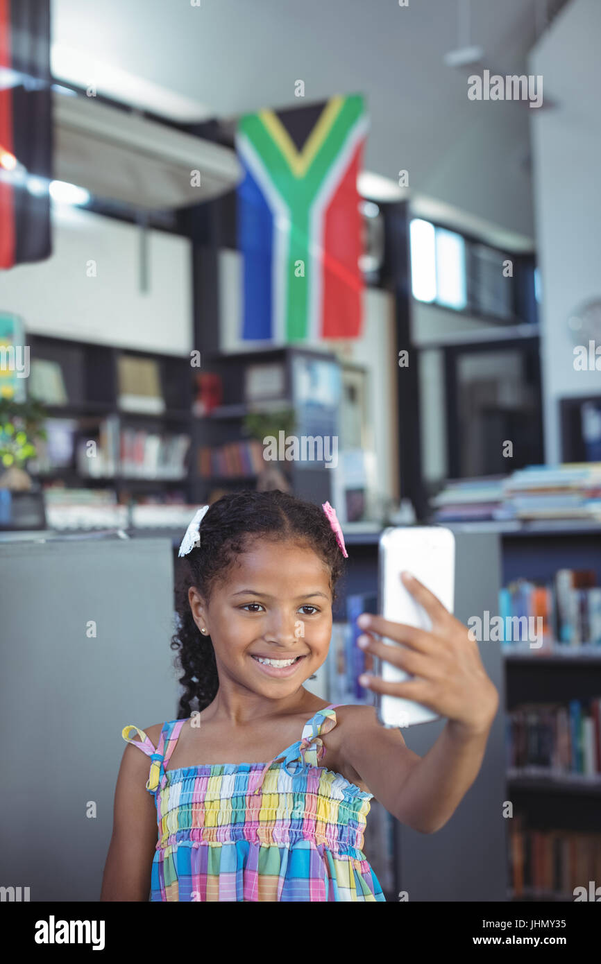 Smiling girl taking selfie while standing in library Stock Photo - Alamy