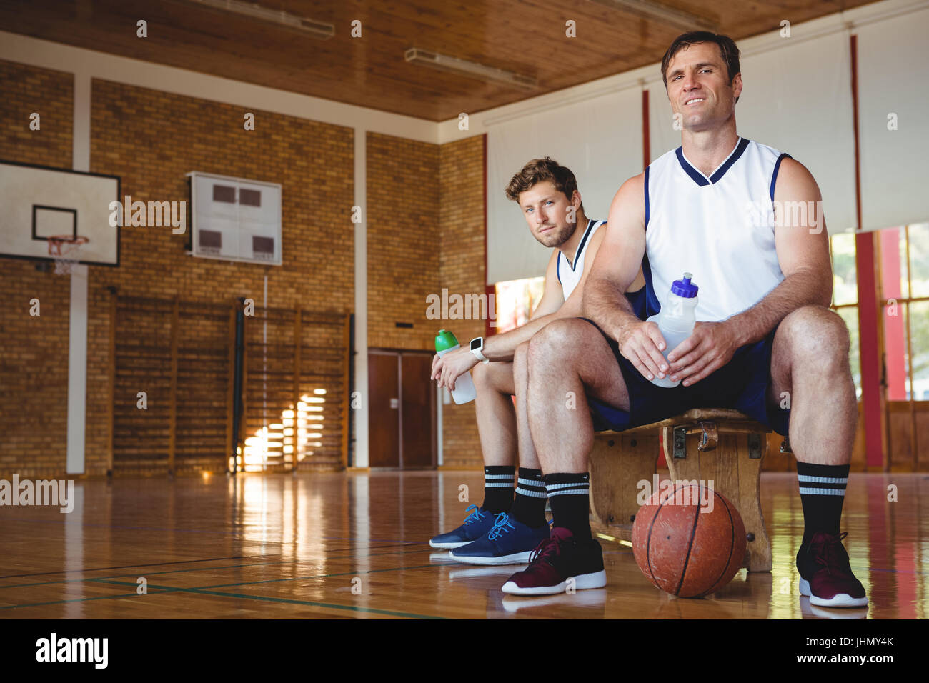 Portrait basketball players looking away while sitting on bench in ...