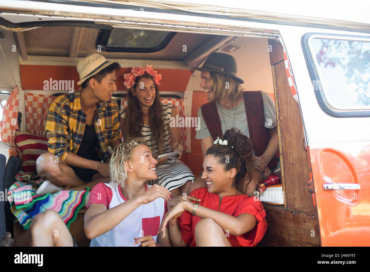 Cheerful young friends sitting together in camper van Stock Photo - Alamy