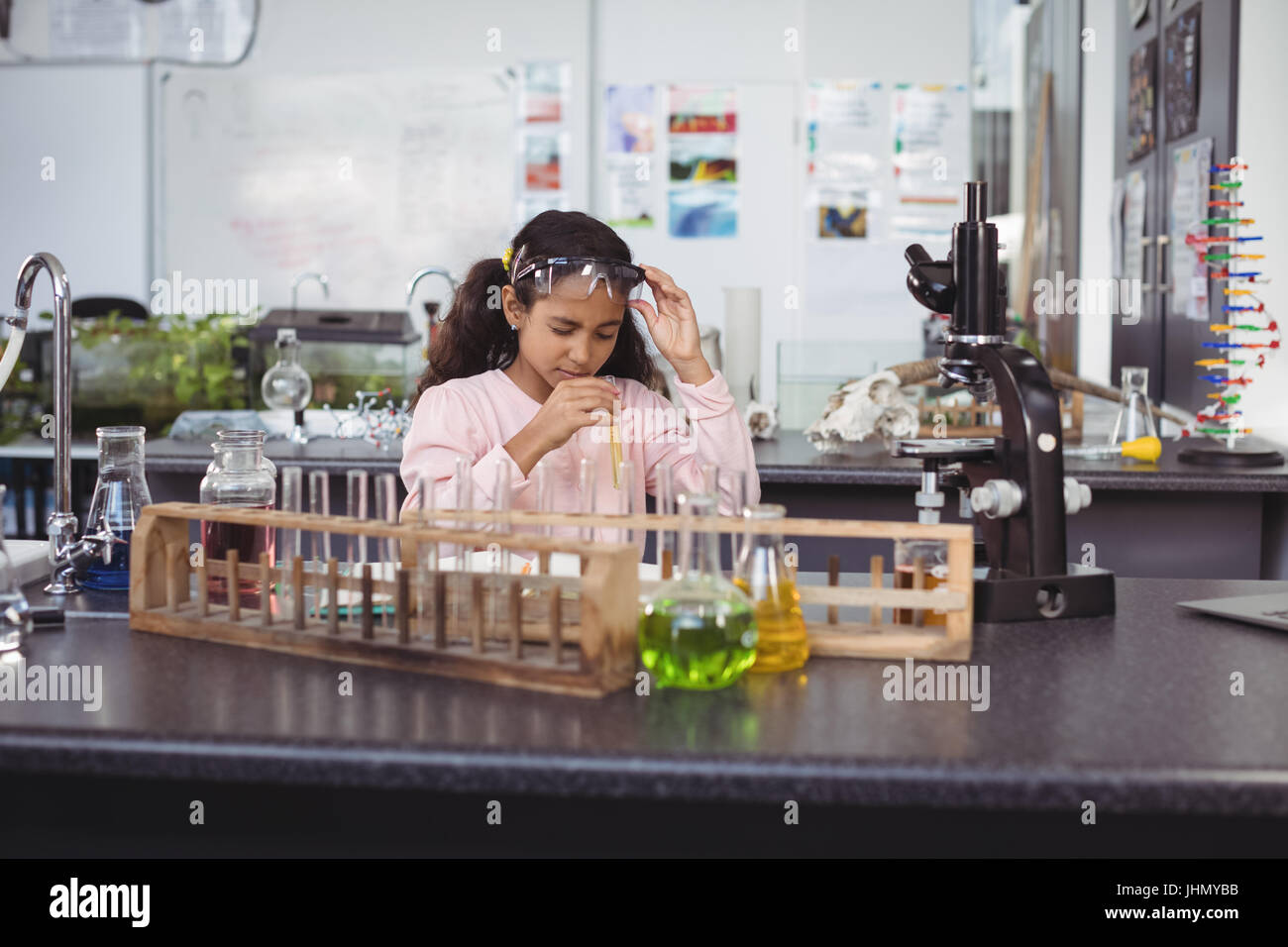 Elementary student holding test tube by desk at science laboratory ...