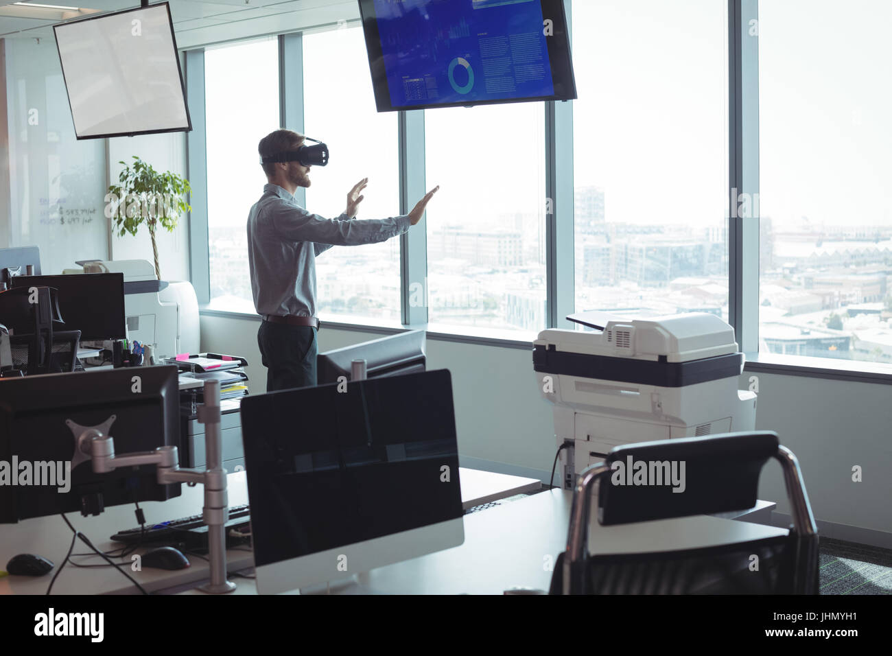 Side view of businessman using virtual reality technology by desk at ...