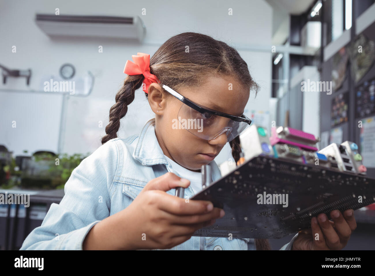 Concentrated elementary student examining circuit board on desk at ...