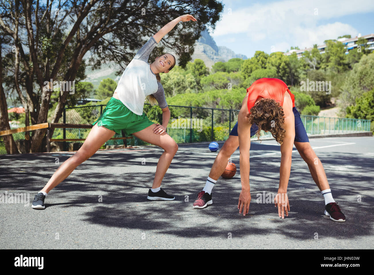 Friends practicing stretching exercise on road against tree Stock Photo ...