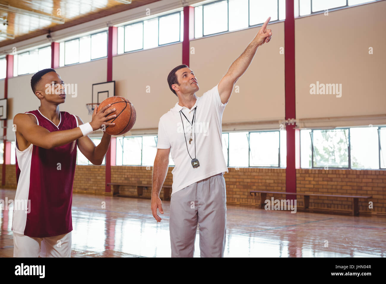 Coach training male teenager while standing in basketball court Stock ...