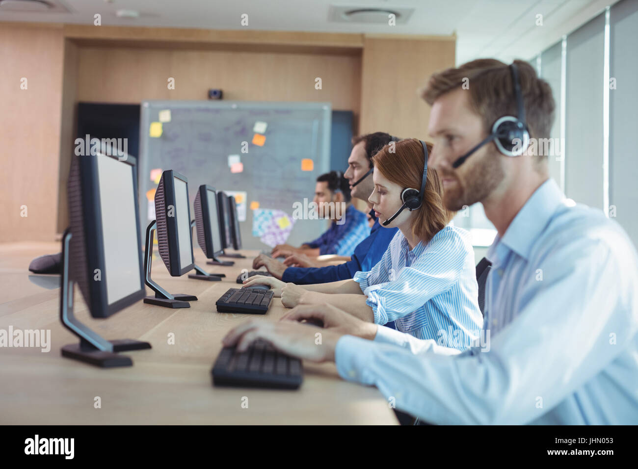 Side view of business people working at desk in call center Stock Photo ...