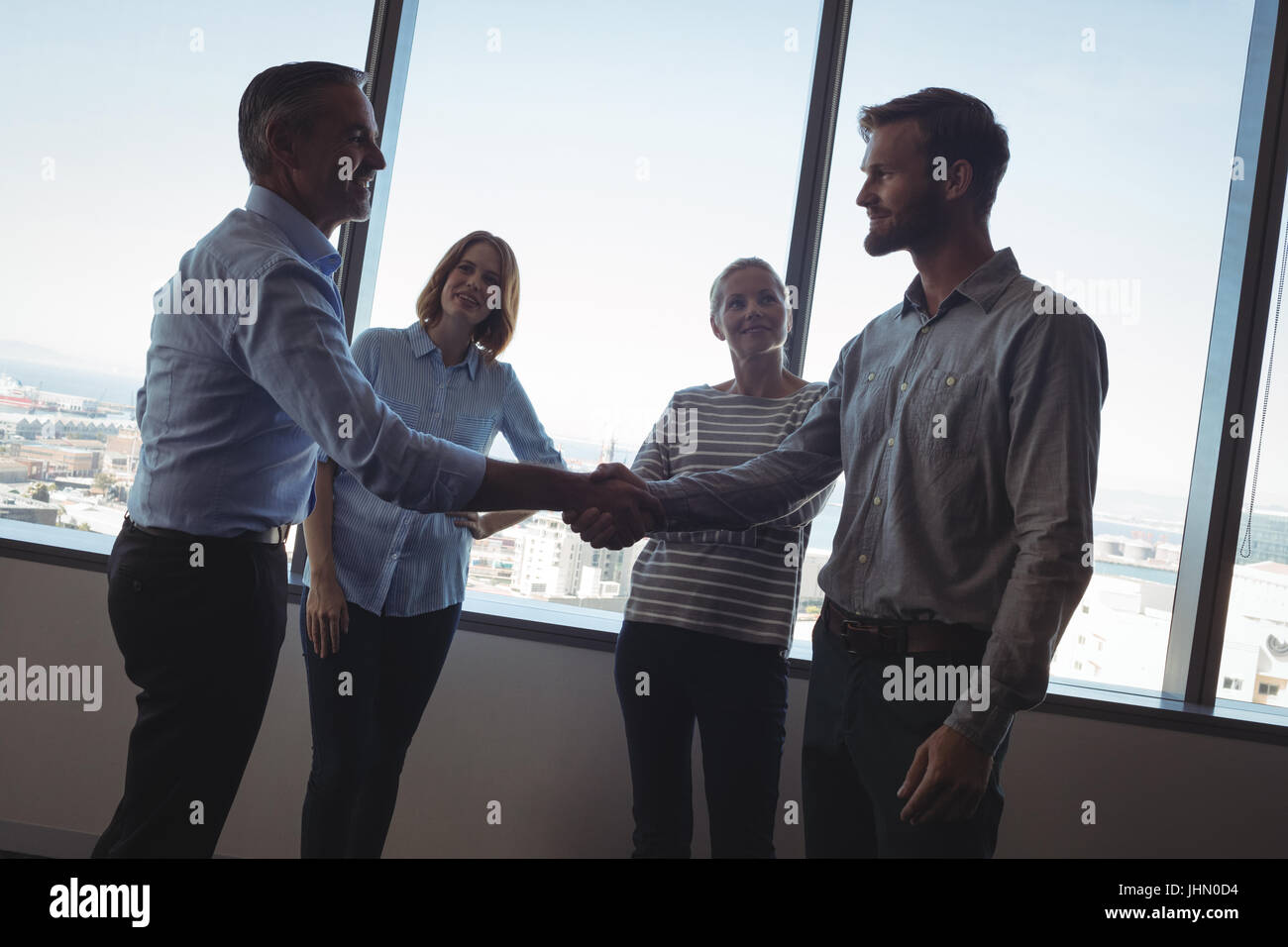 Business people shaking hands against glass windows at office Stock ...
