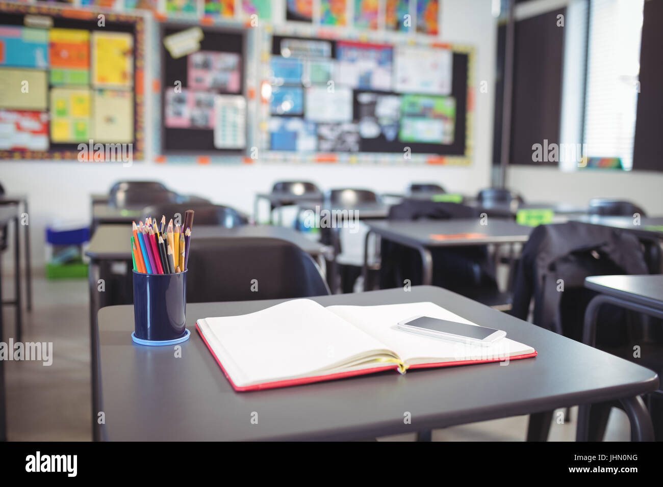 Mobile phone on open book at desk in classroom Stock Photo - Alamy