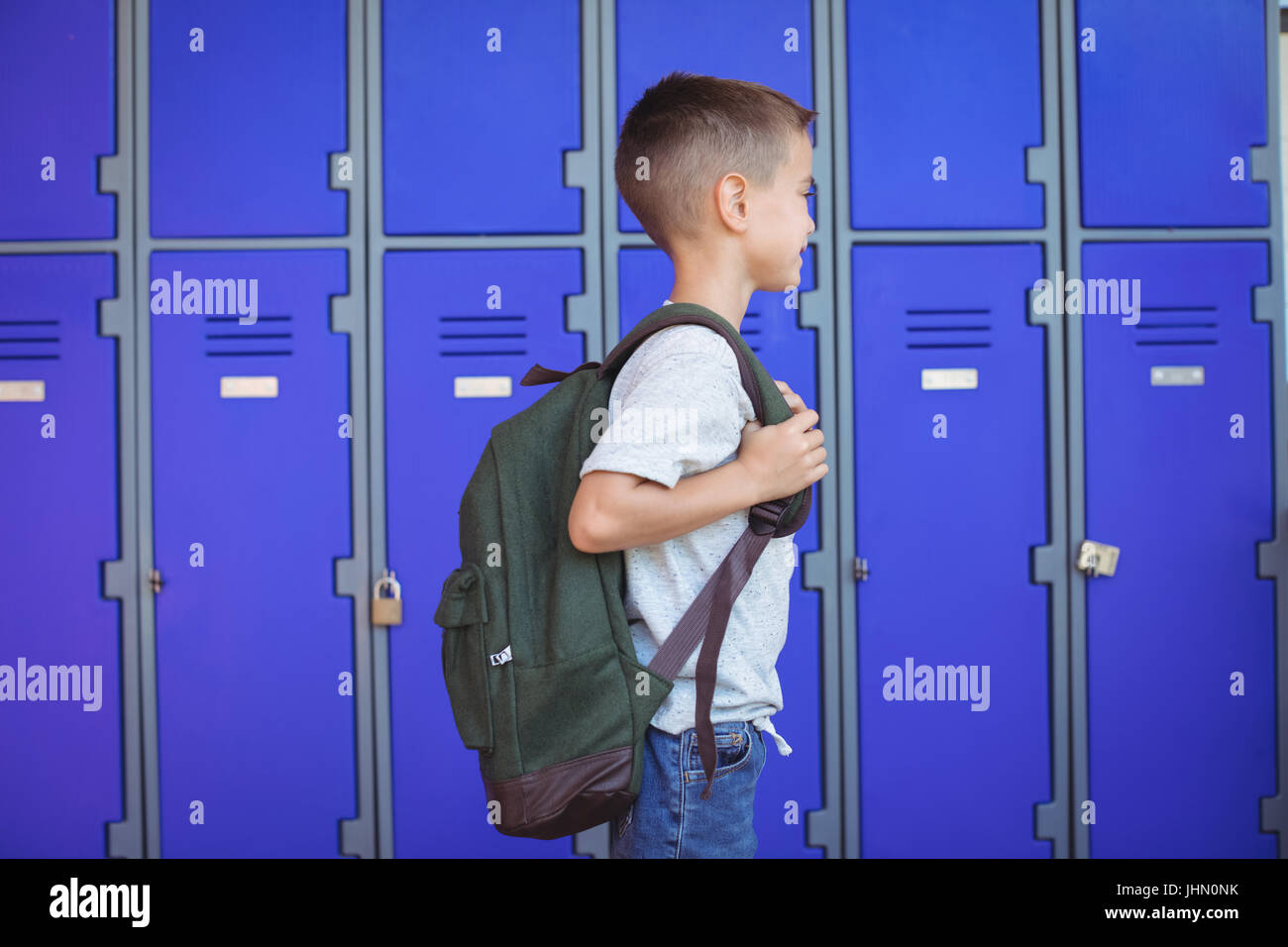 Side view of boy carrying backpack against lockers at school Stock ...