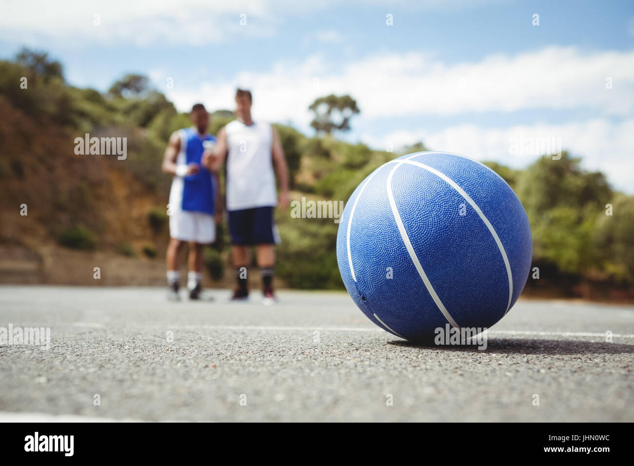 Blue basketball on ground with player standing in background at court ...
