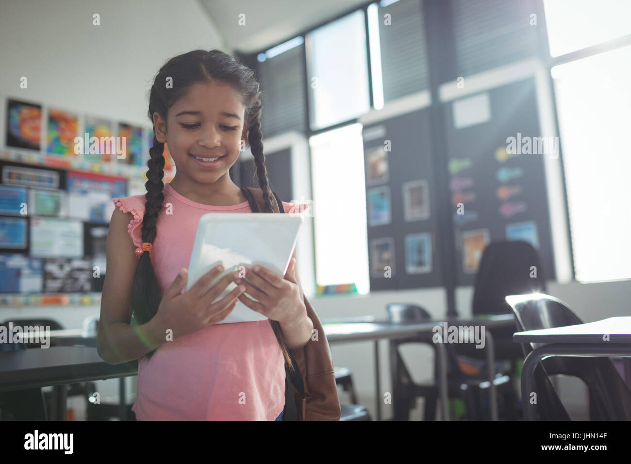 Smiling girl using digital tablet in classroom Stock Photo - Alamy