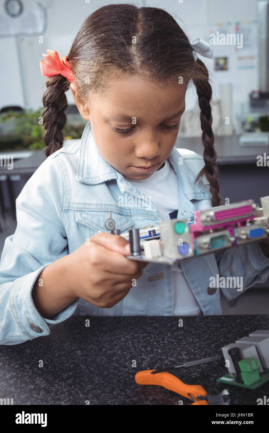 Focused elementary student examining circuit board on desk at ...