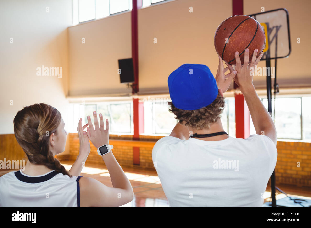 Rear view of coach training basketball player during practise in court ...