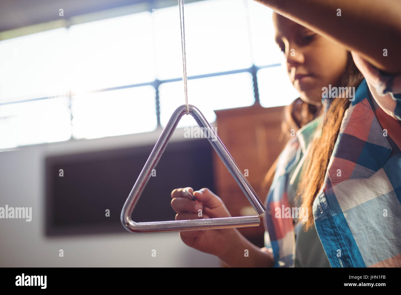 Low angle view of girl playing triangle in classroom at music school ...