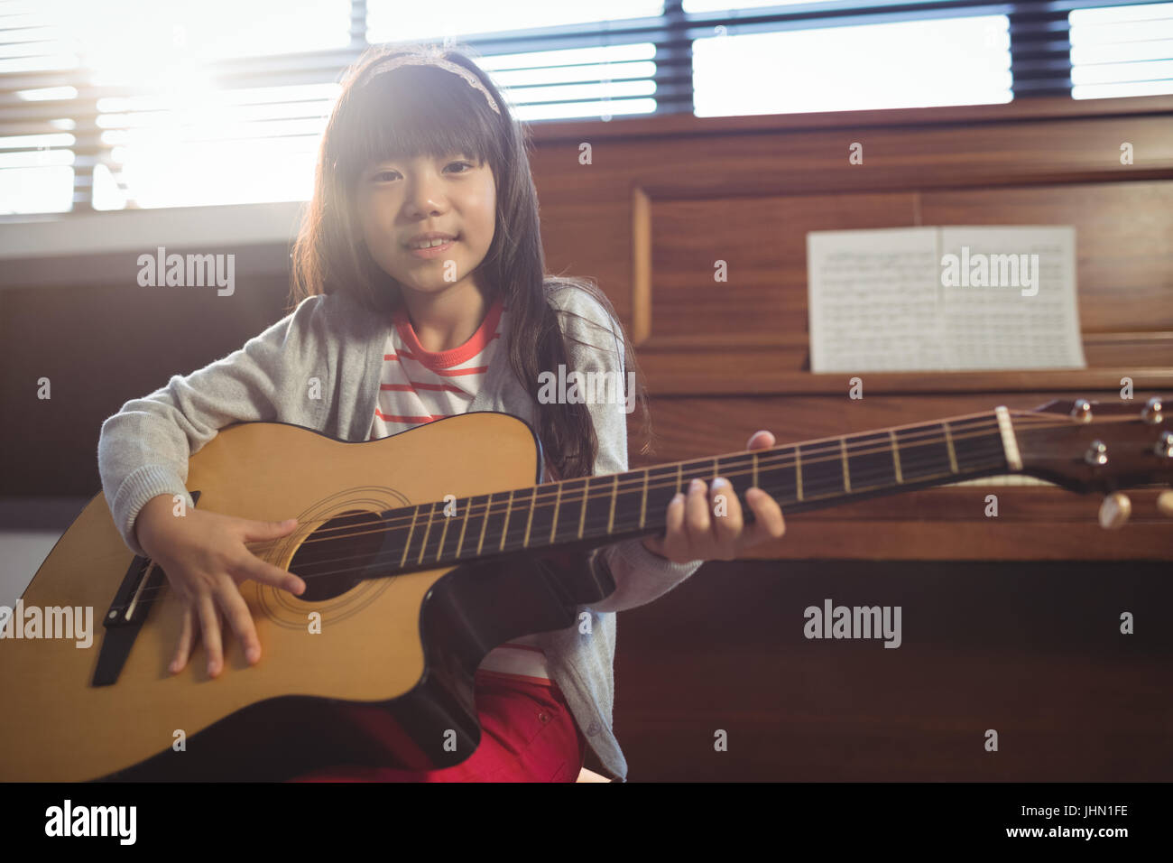 Portrait of girl practicing guitar at music class Stock Photo - Alamy