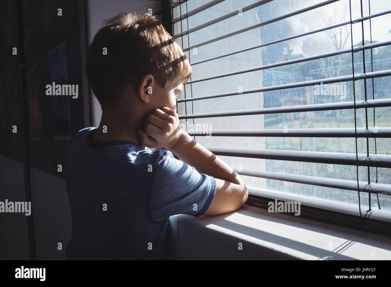 Side view of boy looking through window glass of school Stock Photo - Alamy