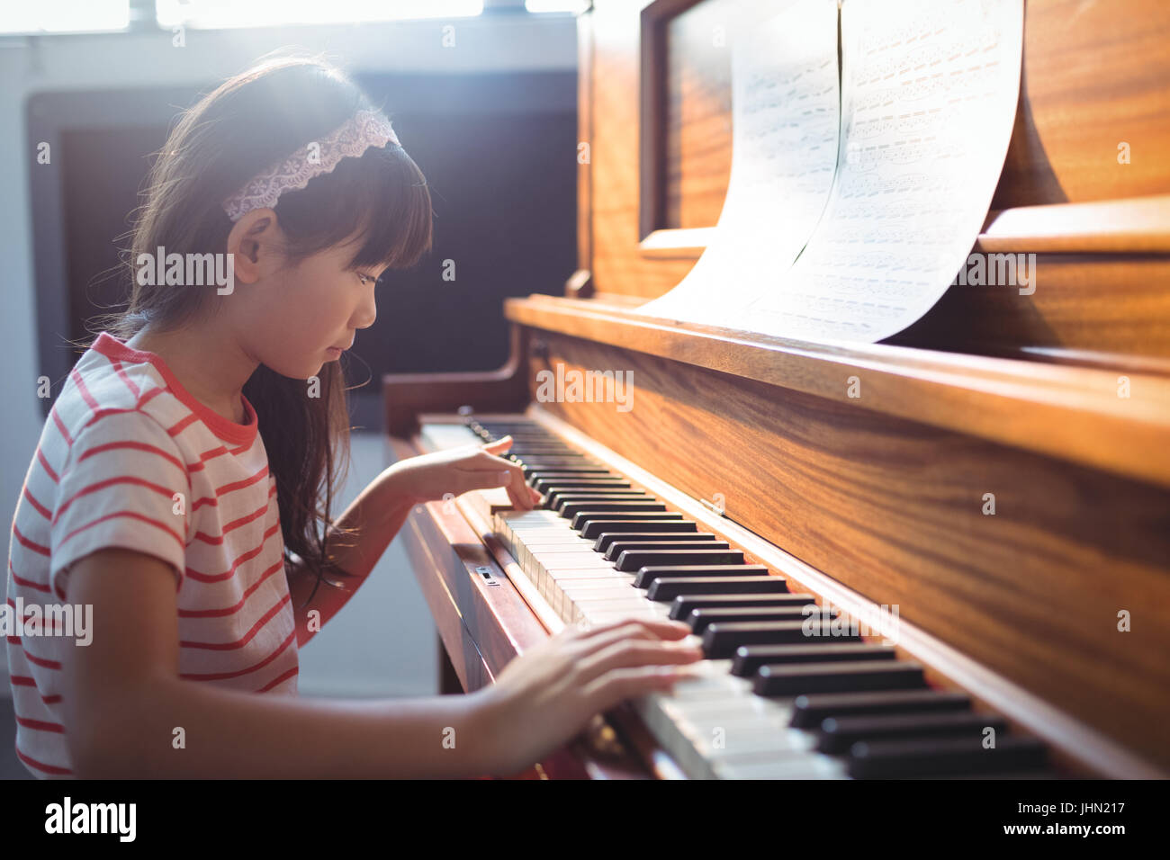 Side view of girl practicing piano in classroom at music school Stock ...