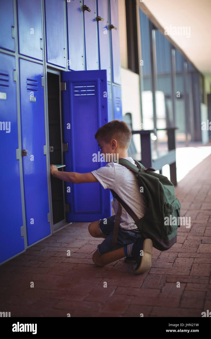 Side view of boy taking books from locker at school corridor Stock ...