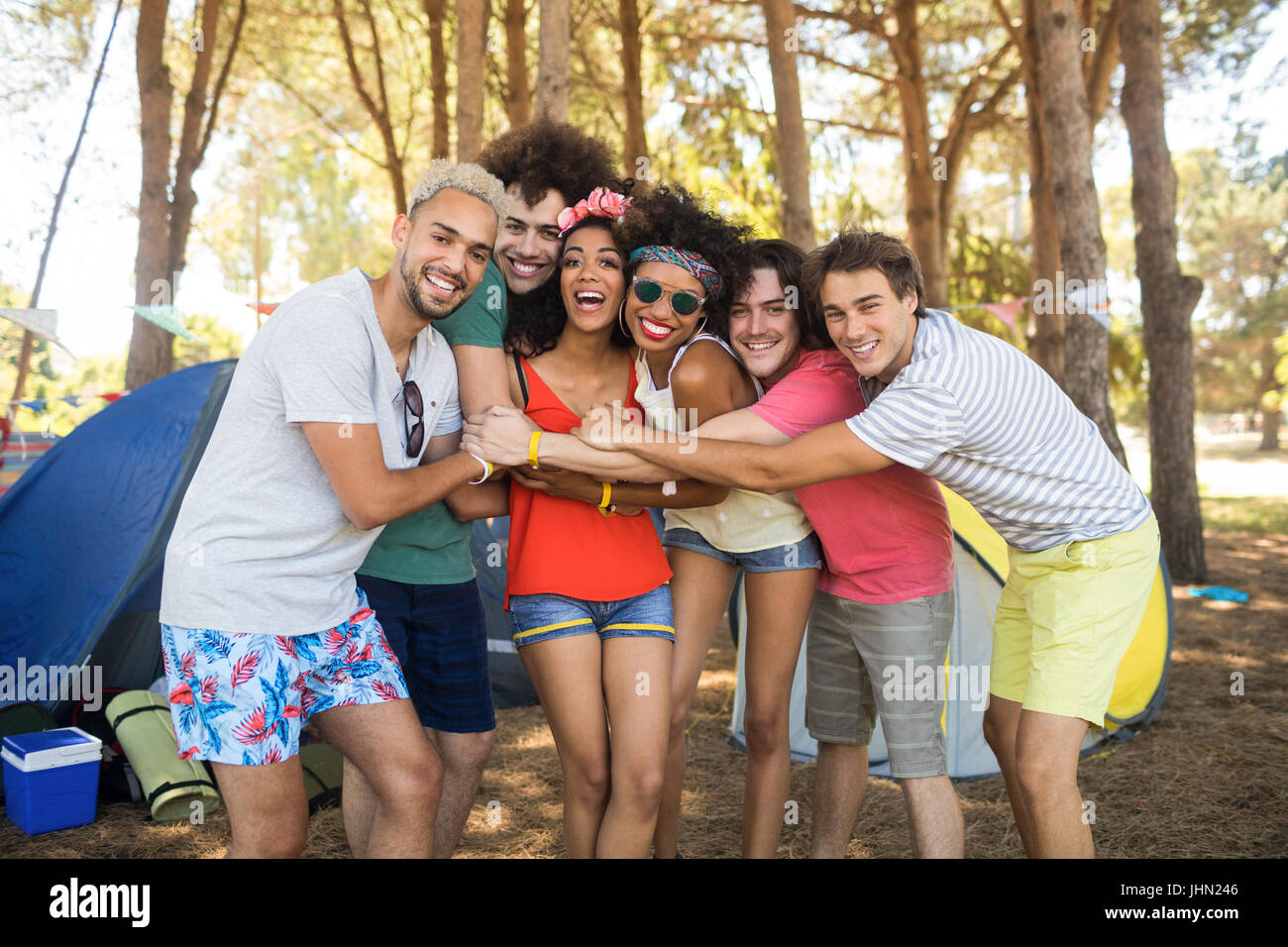 Portrait of cheerful friends embracing while standing on field at ...