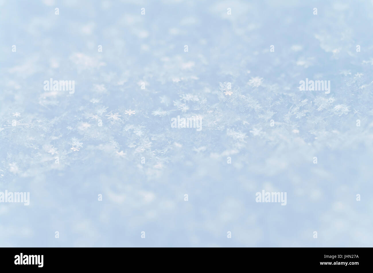 light blue background macro image of top layer of snow with separate ...