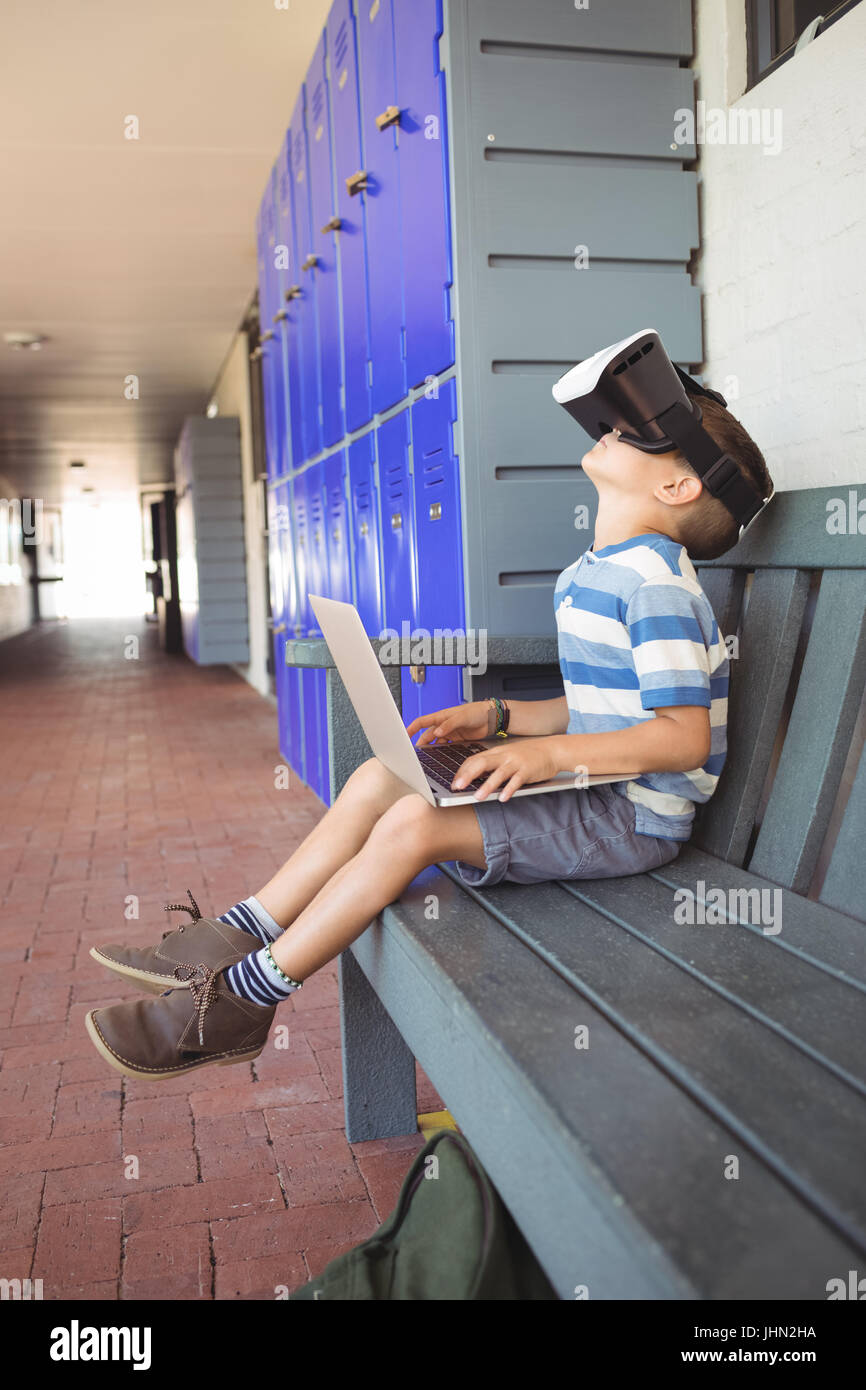 Side view of boy using laptop and virtual reality glasses while sitting ...