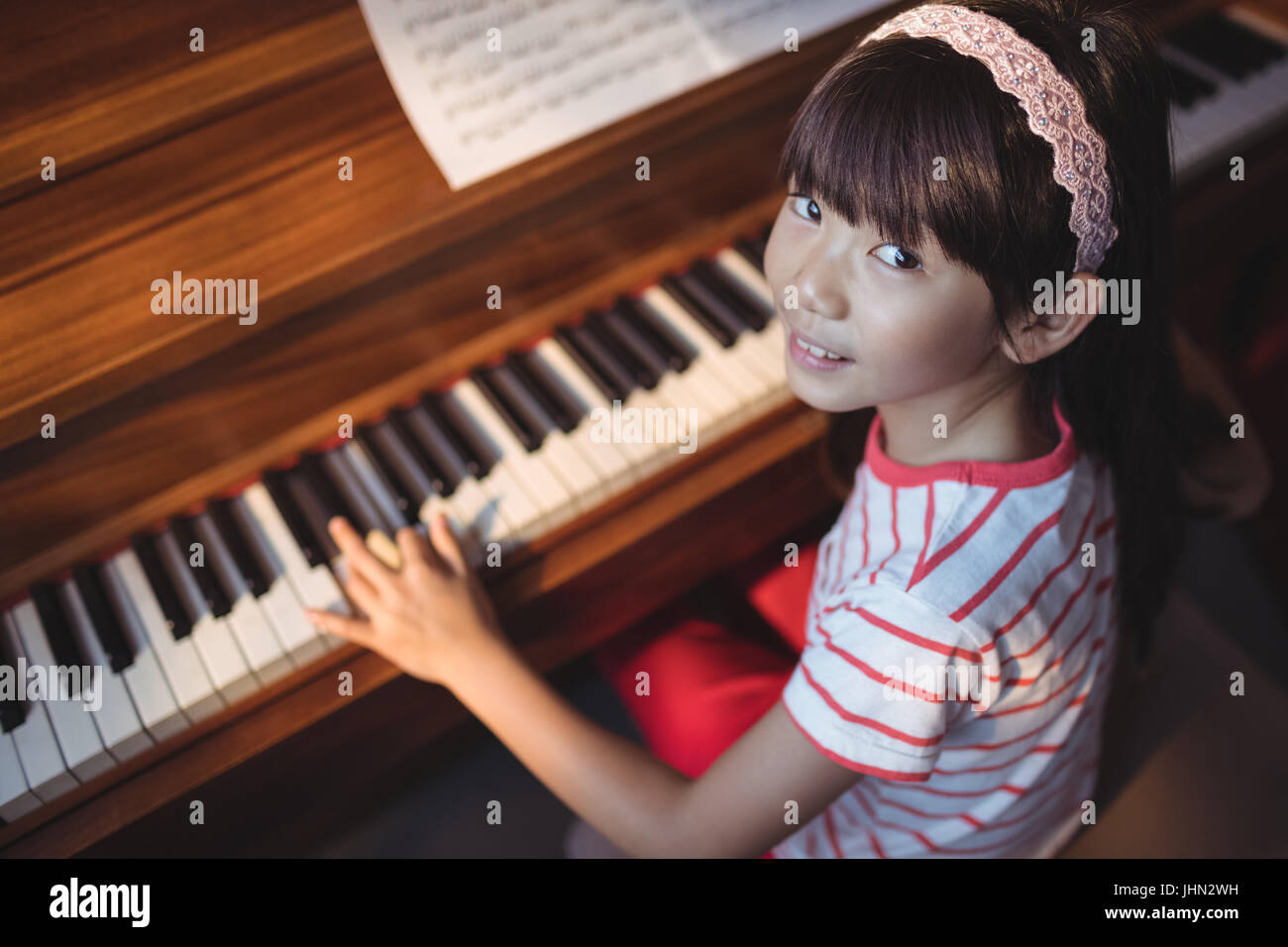 High angle portrait of girl practicing piano in classroom at music ...