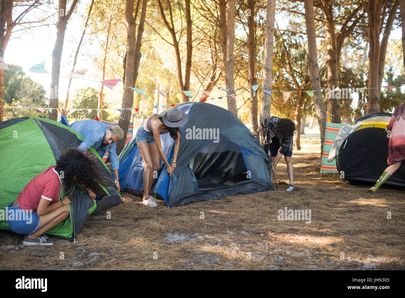 Friends setting up their tents together on field at countryside Stock ...