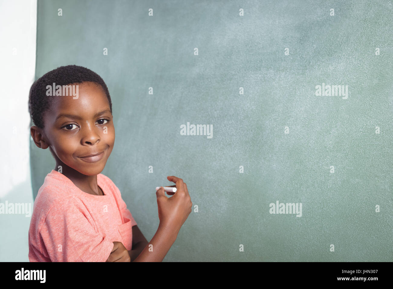 Portrait of boy standing by greenboard in classroom Stock Photo - Alamy