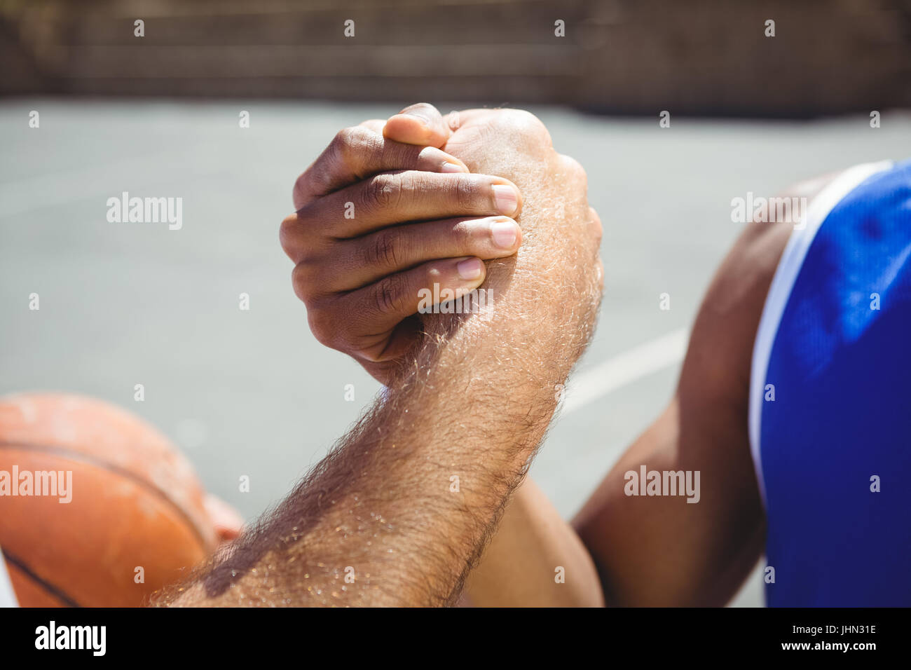 Cropped image of basketball players holding hands while playing in ...